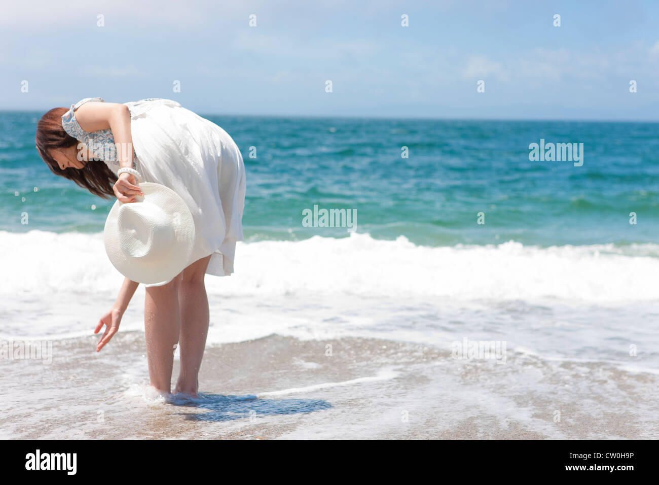 Woman on beach touching water Stock Photo - Alamy