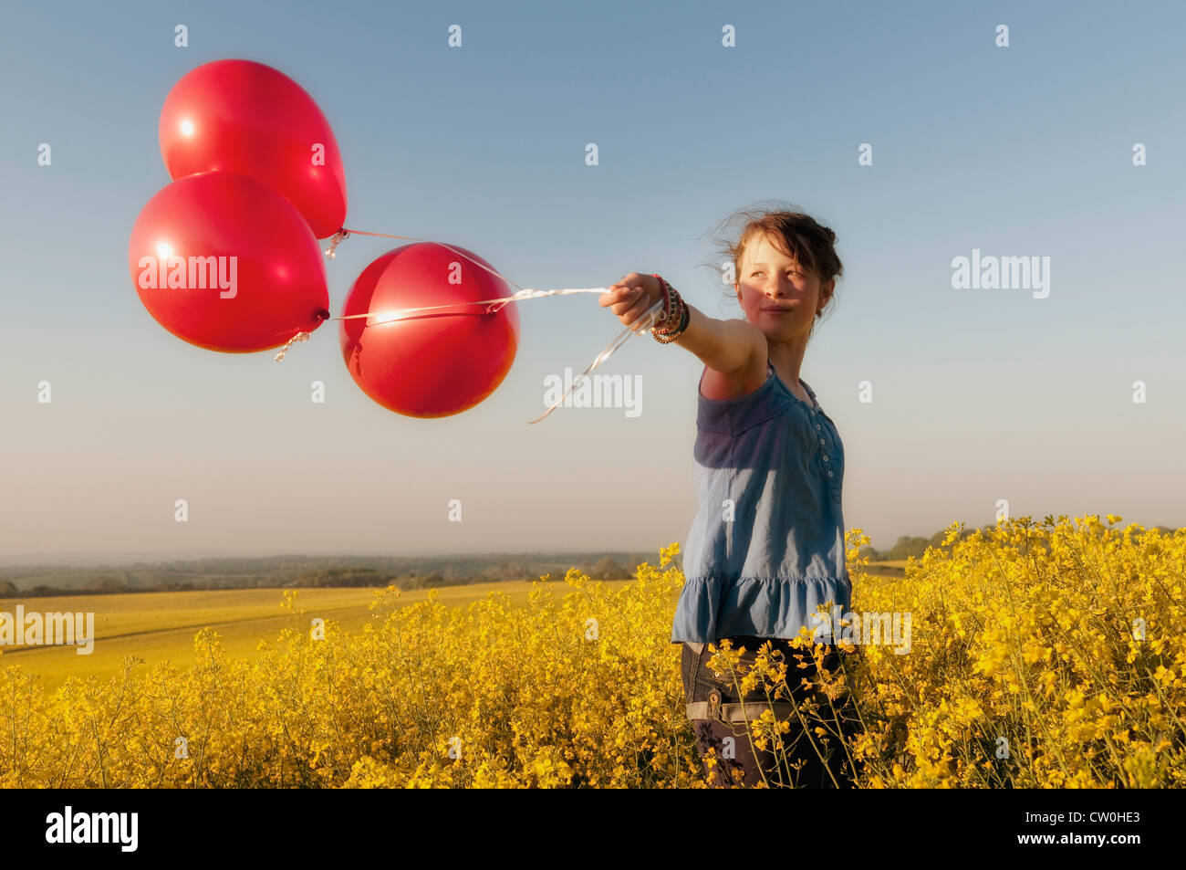 Girl carrying balloons in field Stock Photo - Alamy