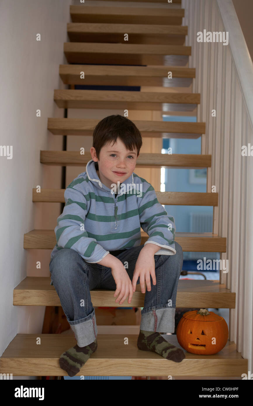 Boy sitting on steps with carved pumpkin Stock Photo - Alamy