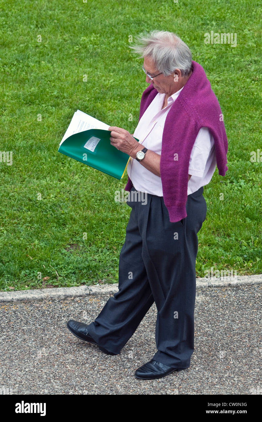 Overhead view of man reading whilst walking along pavement - France ...