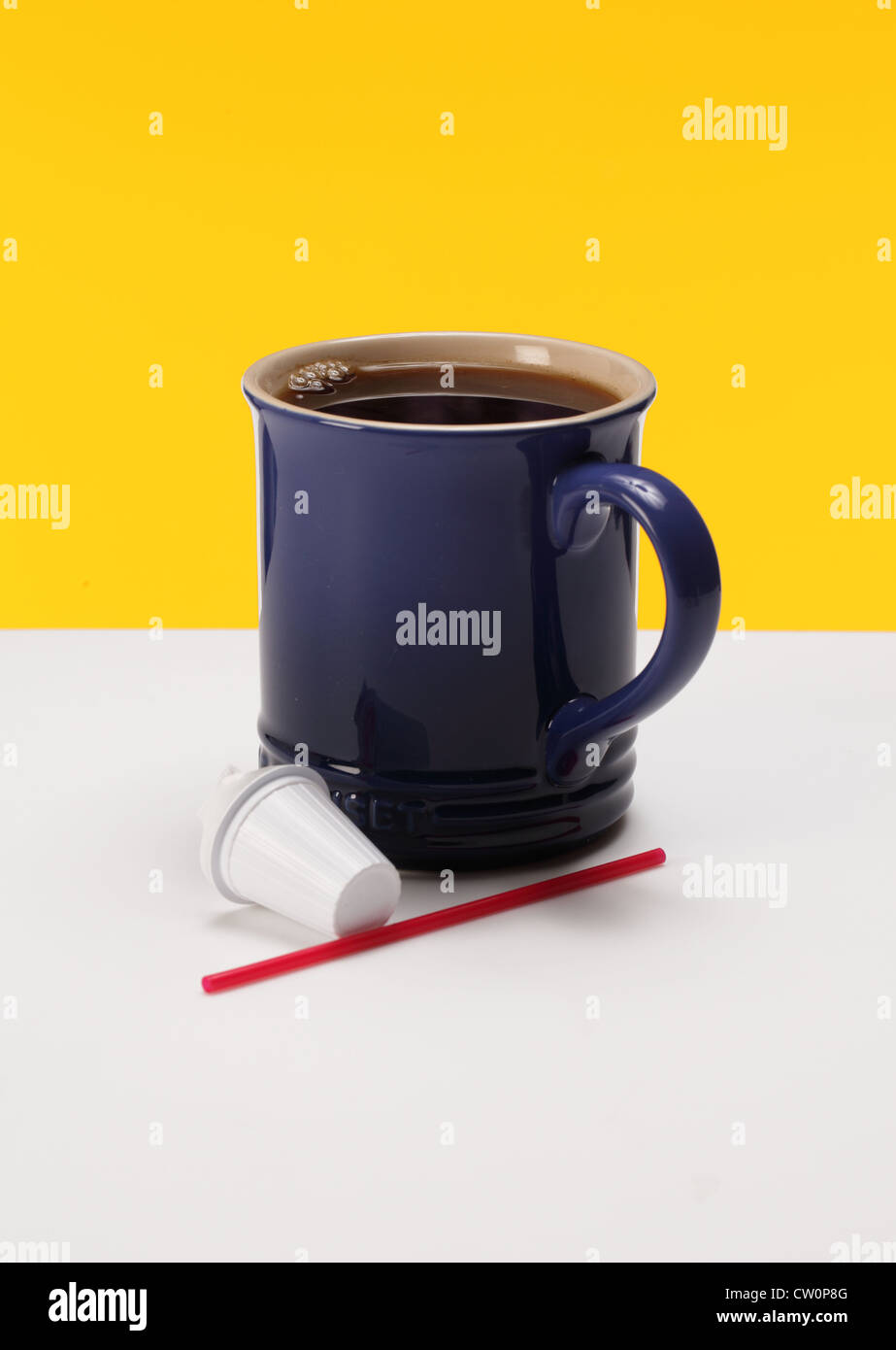 A coffee mug with a red stir stick,and creamer packet Stock Photo - Alamy