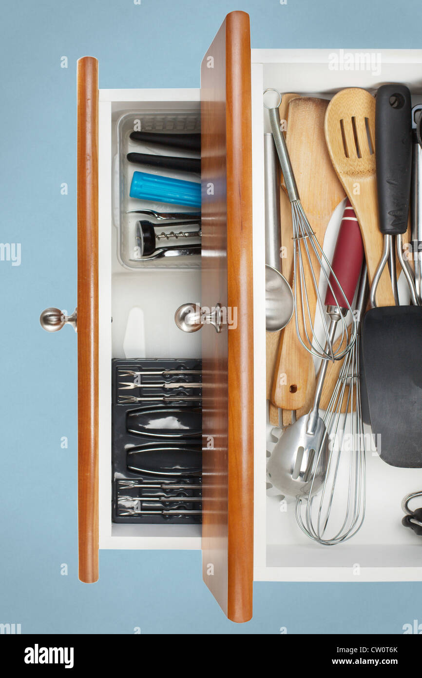 Open Kitchen Drawer with utensils on display with light blue background ...