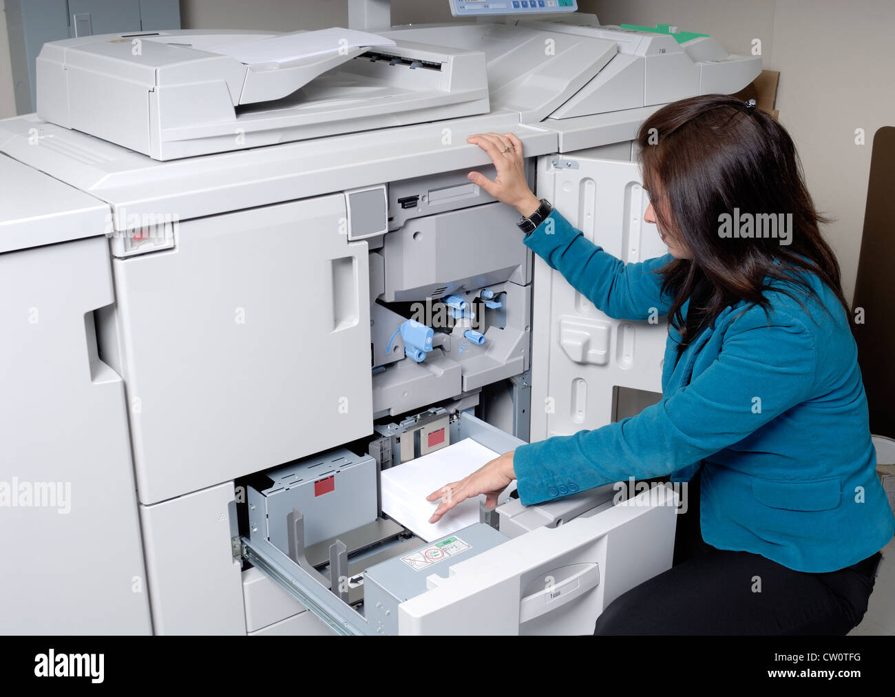 Young Woman Loading Paper Into A Tray Of A Photocopying Machine At The ...