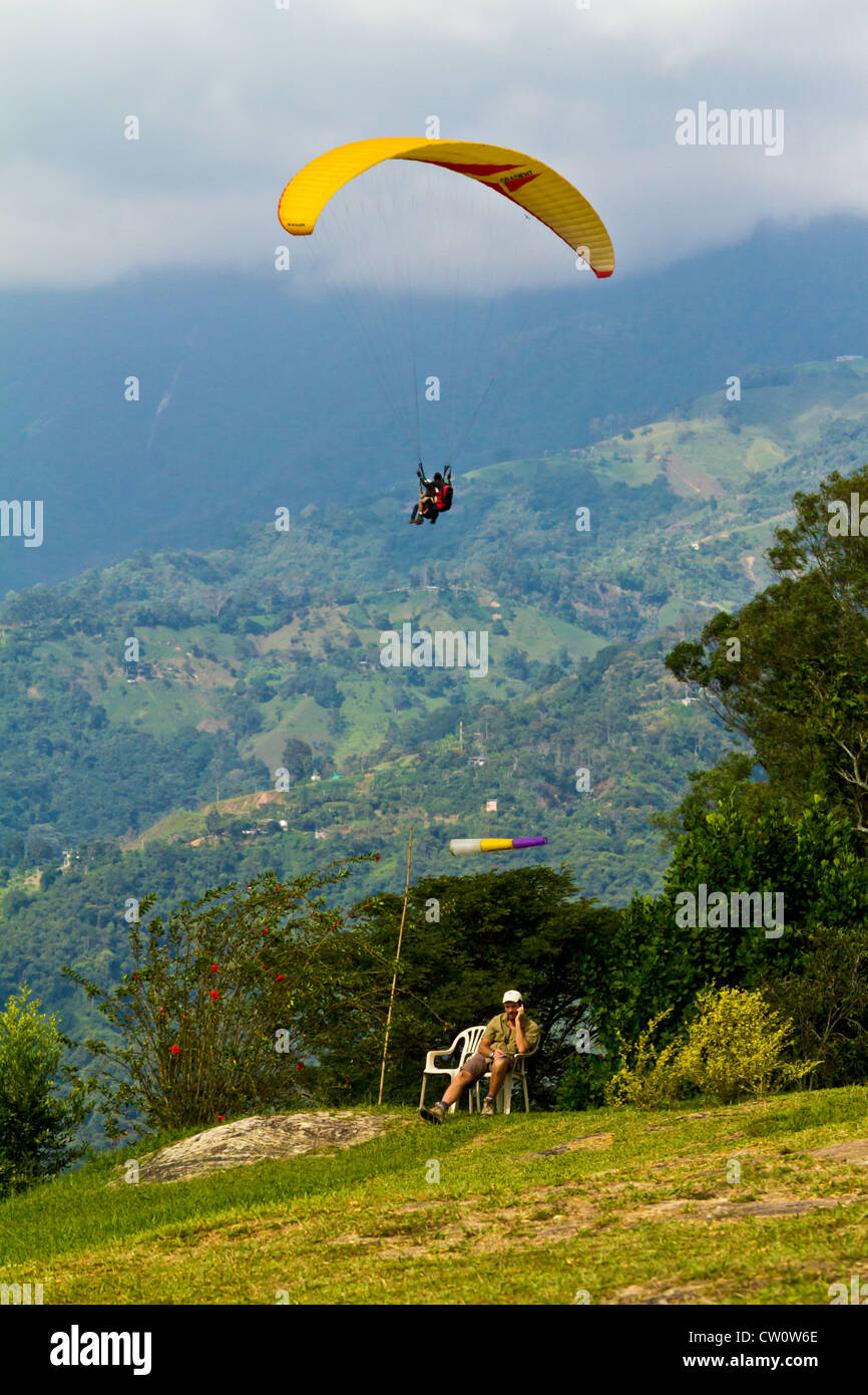 Seated man and windsock as a paraglider soars overhead in Buccaramanga ...