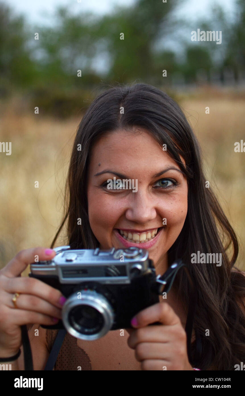 Cute young woman using an old camera Stock Photo - Alamy