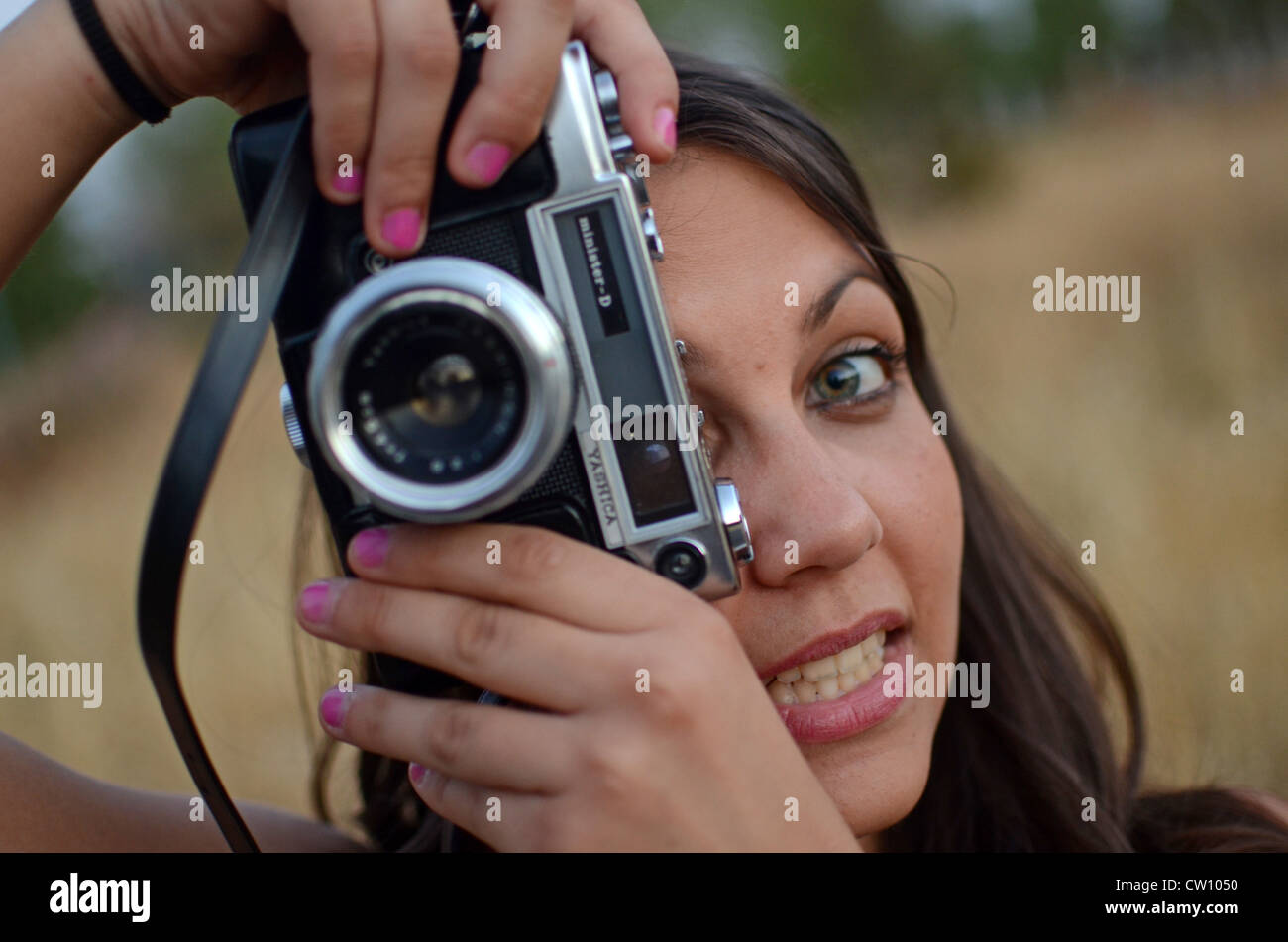 Cute young woman using an old camera Stock Photo - Alamy