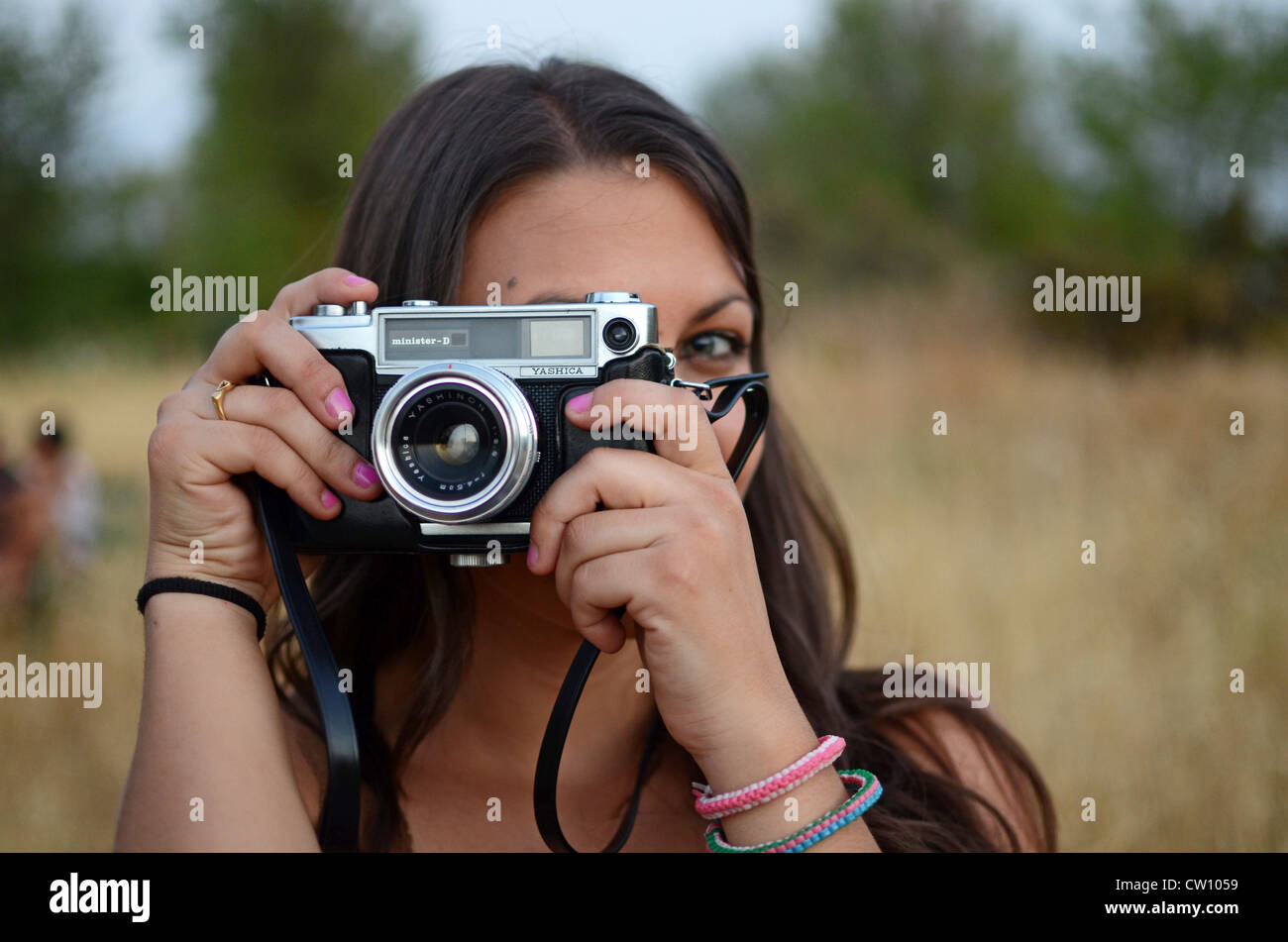 Cute young woman using an old camera Stock Photo - Alamy