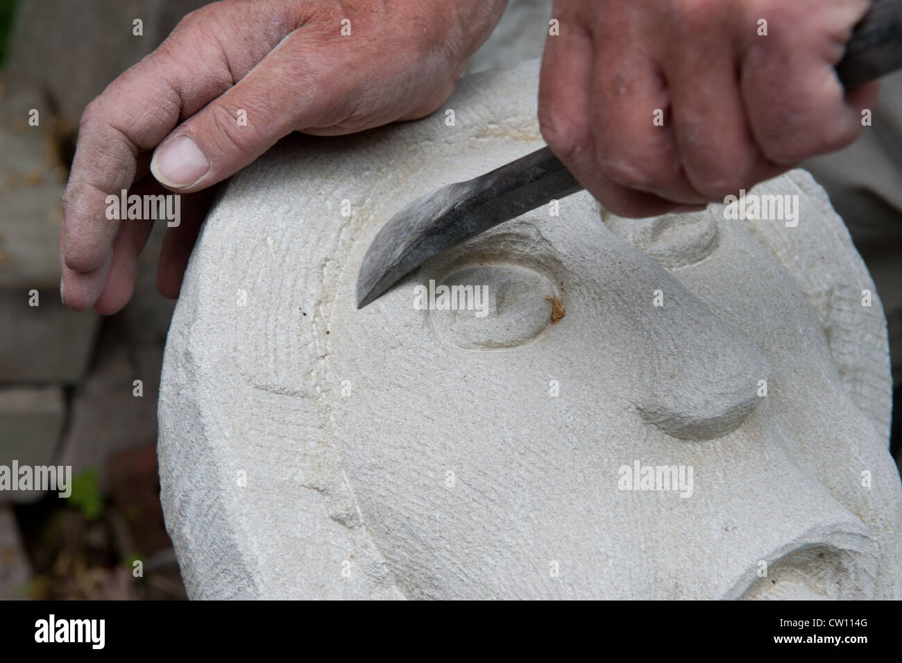 Stonecarver chiseling feature on sculpture Stock Photo - Alamy