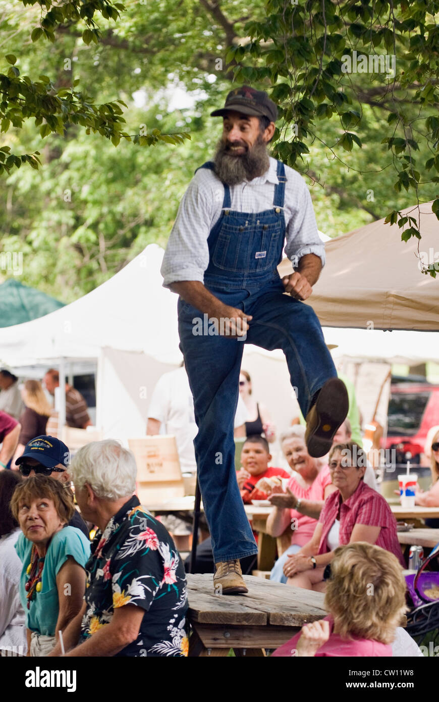 Man in Bib Overalls Dancing a Jig on a Picnic Table Amid Crowd at the ...