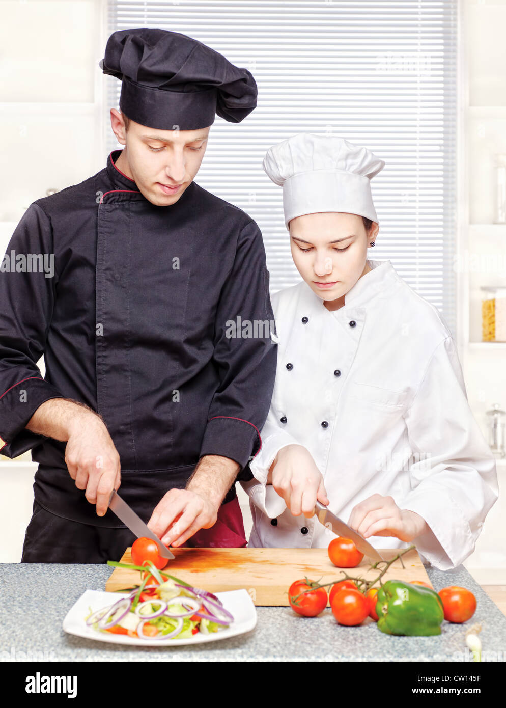 Senior chef teaches young chef to properly cut vegetables Stock Photo ...