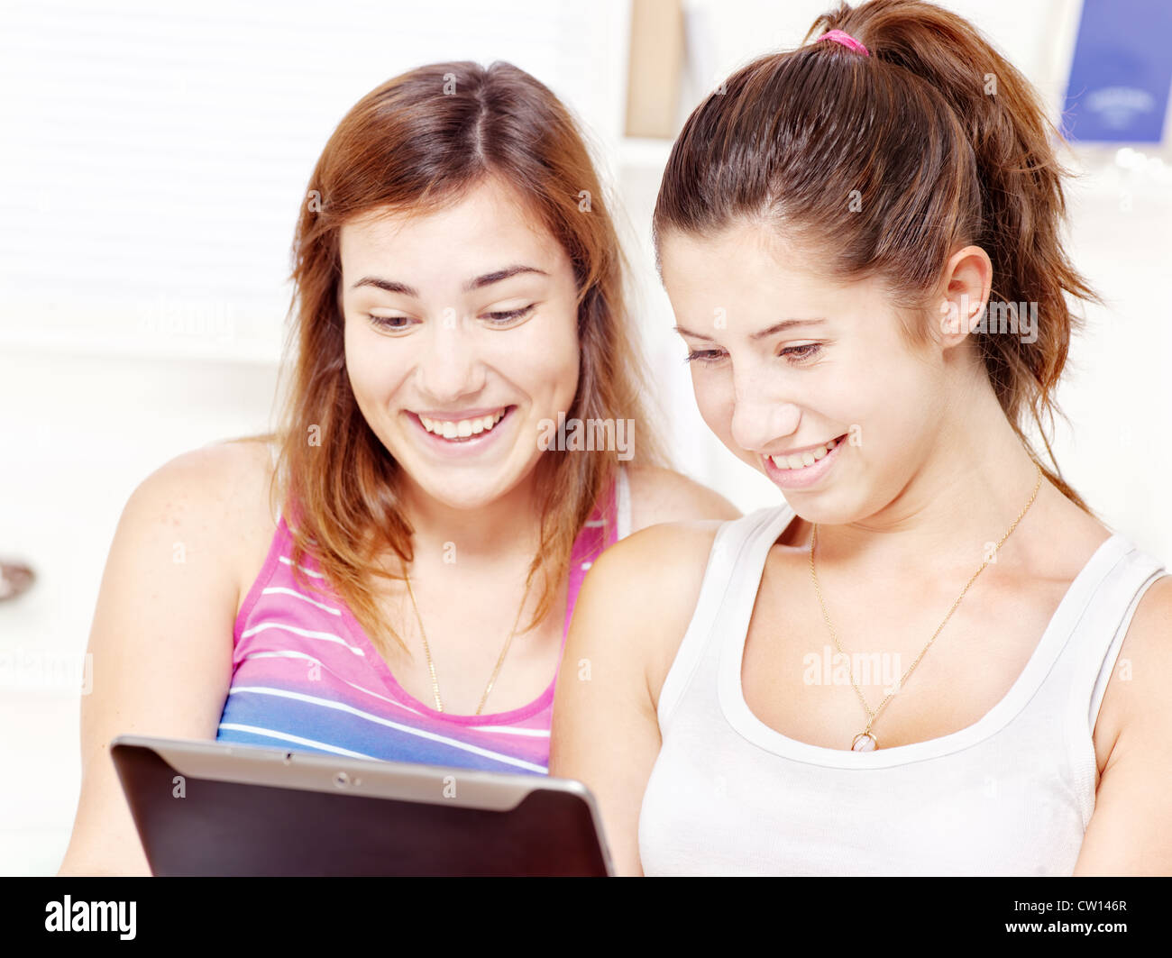Two happy teenage girls using tablet computer at home Stock Photo - Alamy