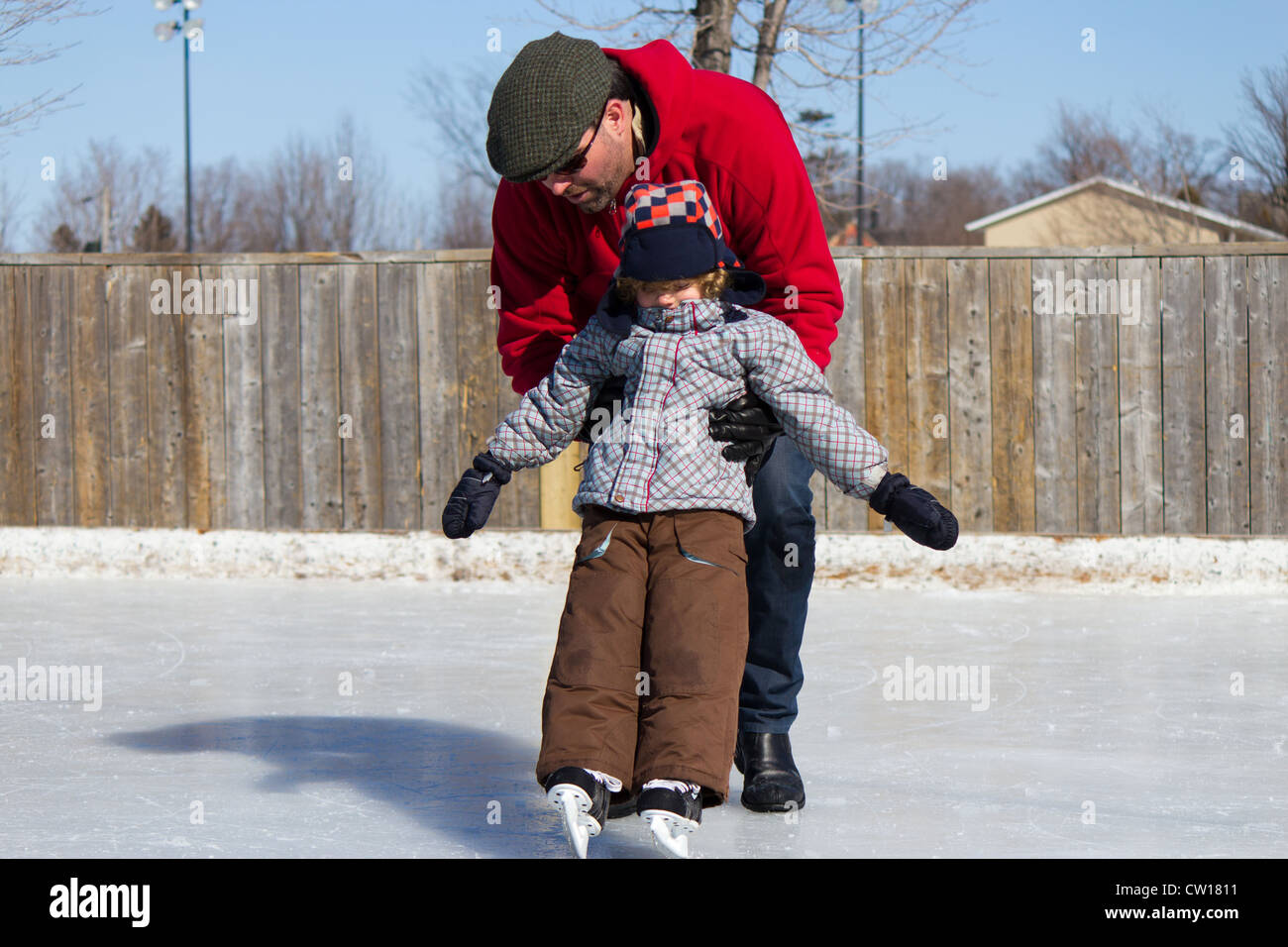 Father teaching son how to ice skate at an outdoor skating rink in ...