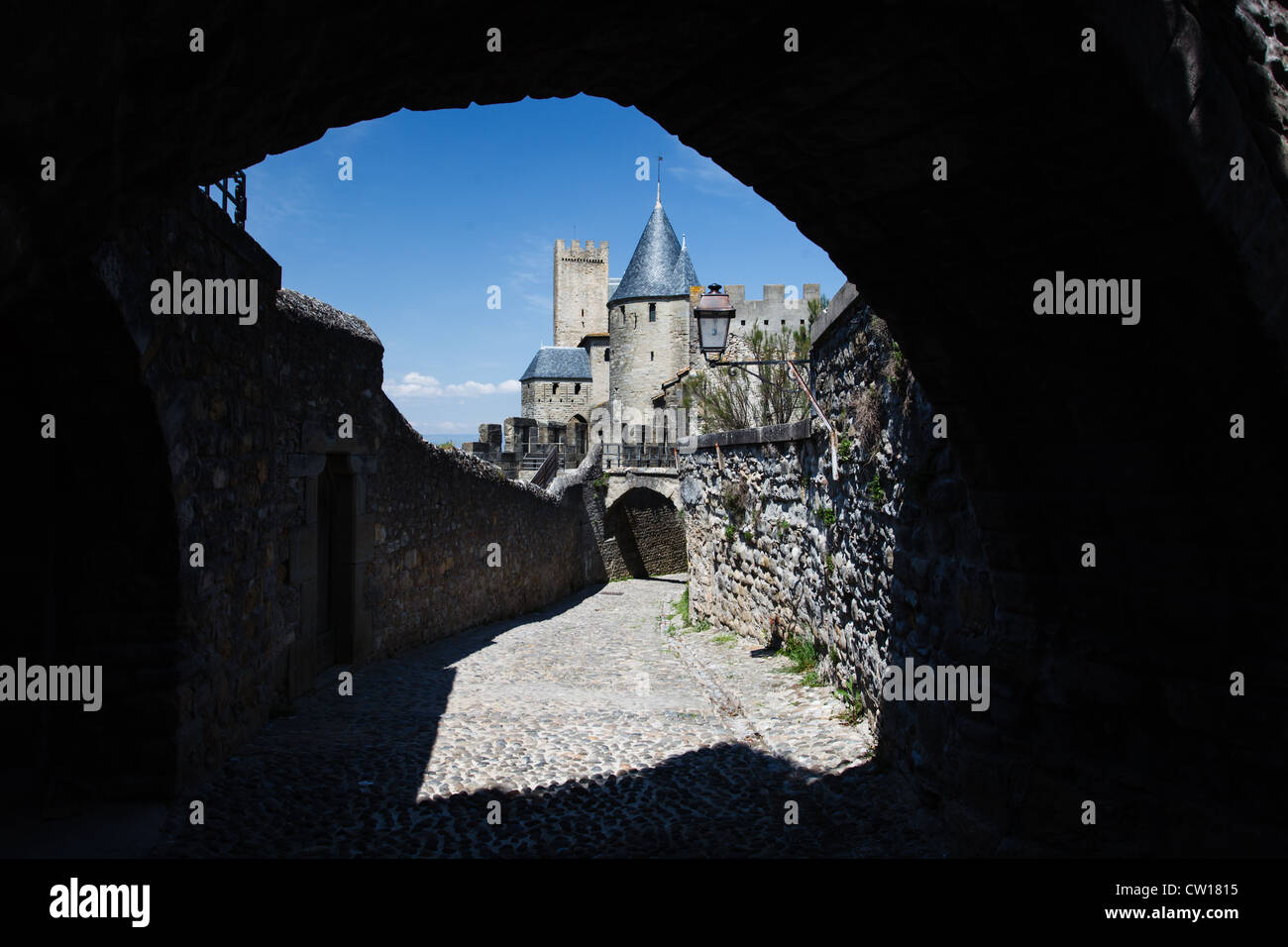 View of castle towers and chateau through an arch in the rampart wall ...