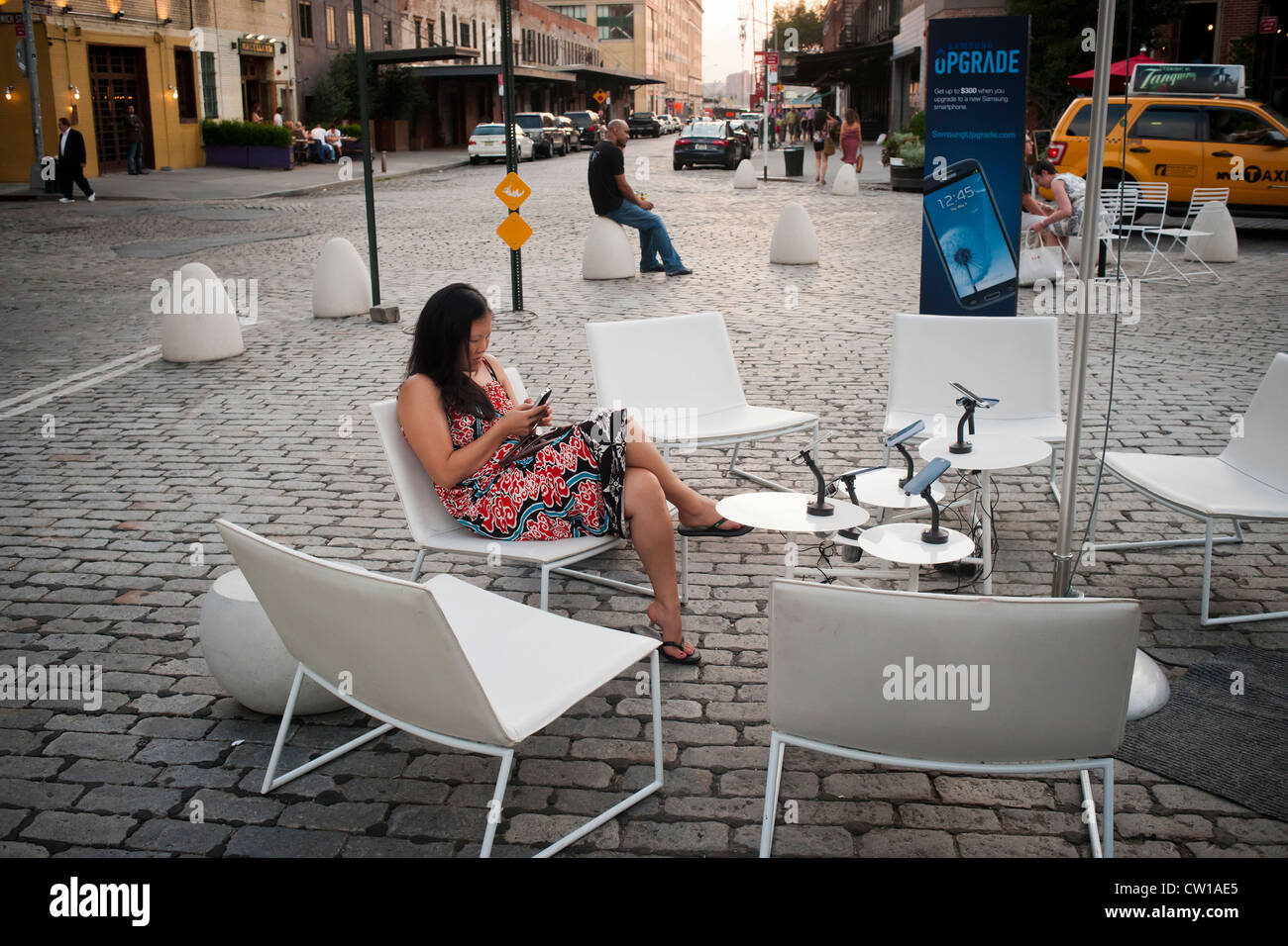 Woman uses a cell phone at a Samsung promotional kiosk to introduce ...