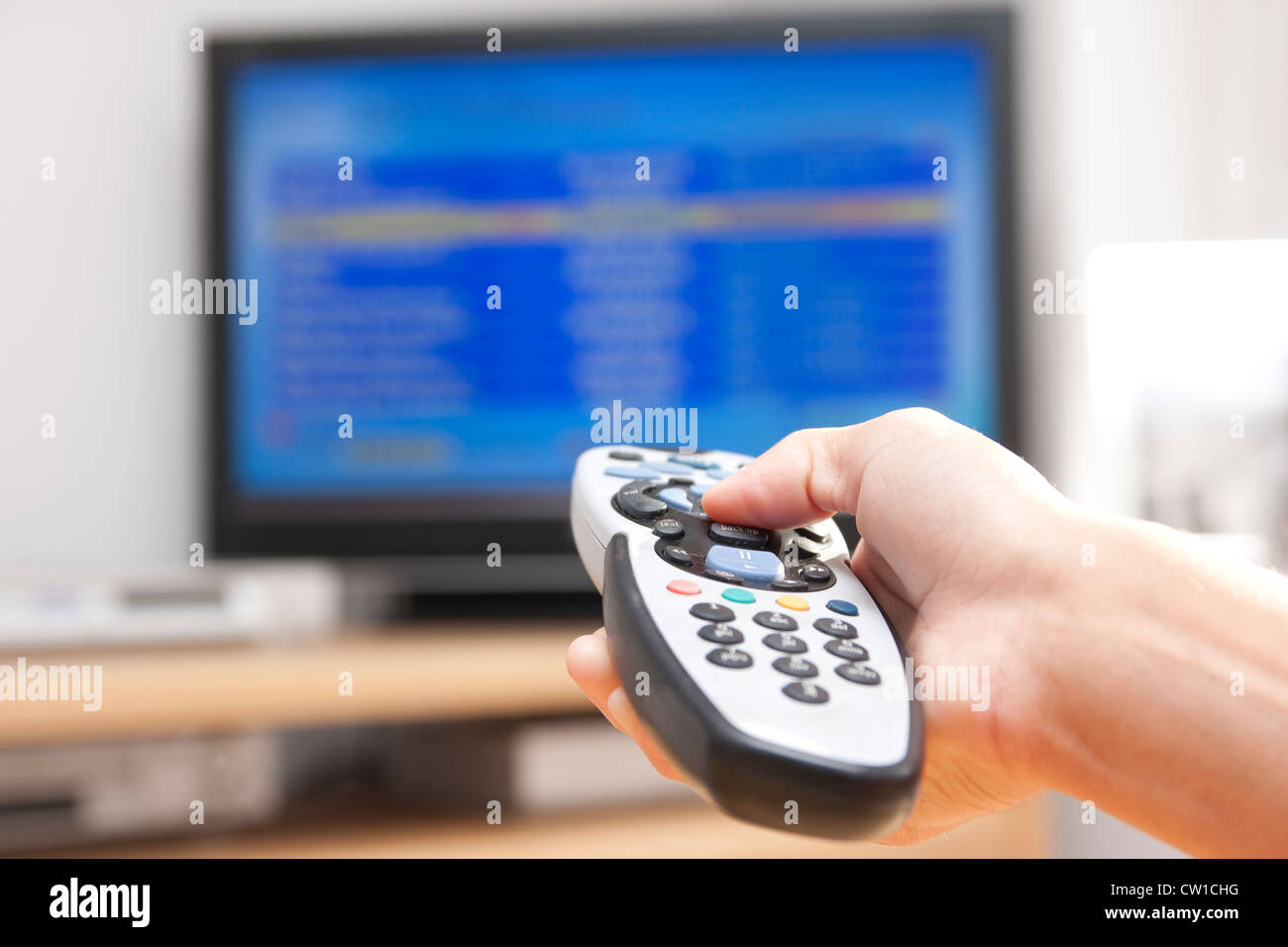 adult hand holding remote with tv in background Stock Photo - Alamy