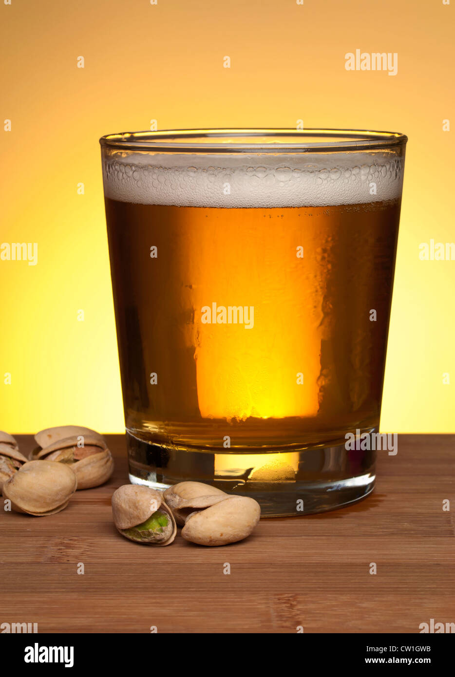 Cold delicious frothy beer in glass with nuts on wood table against ...