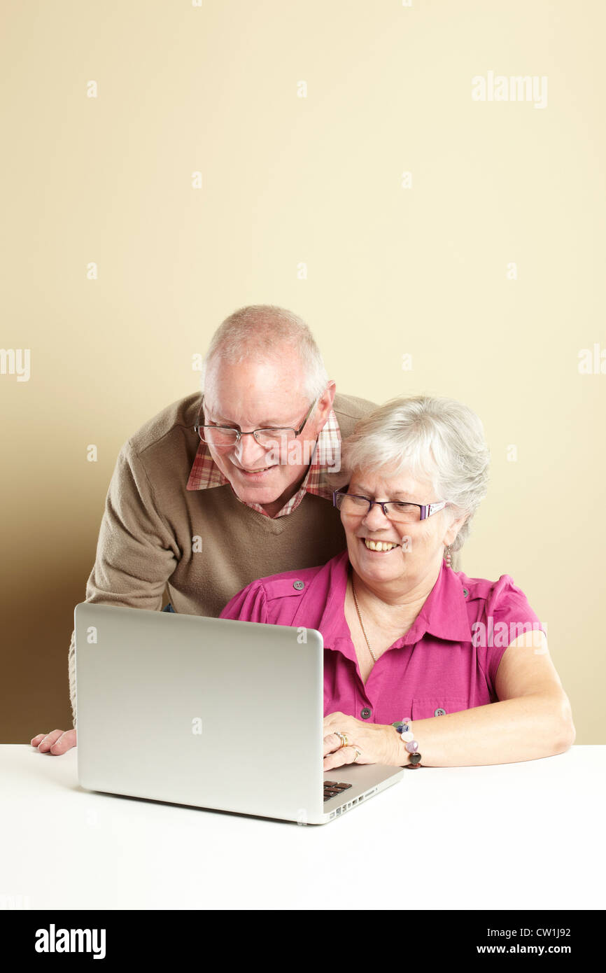 Senior man and woman using laptop whilst looking happy Stock Photo - Alamy