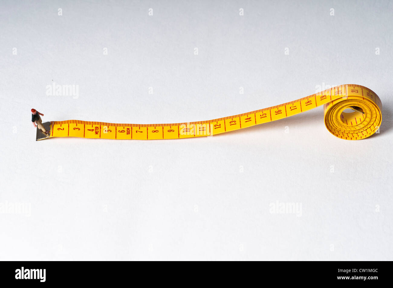 Toy figure climbing a tape measure Stock Photo - Alamy