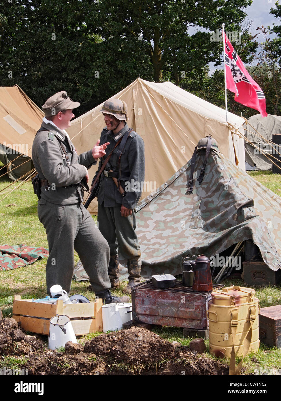 Two German soldiers talking in camp, with German flag and tents at ...