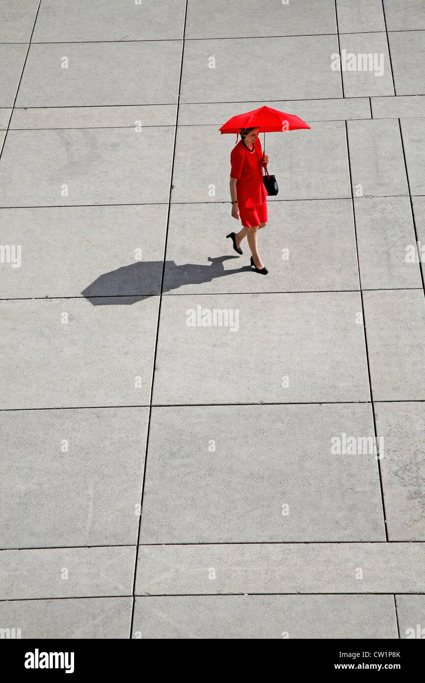 Lady in red dress with red umbrella is walking outdoors in pattern of ...