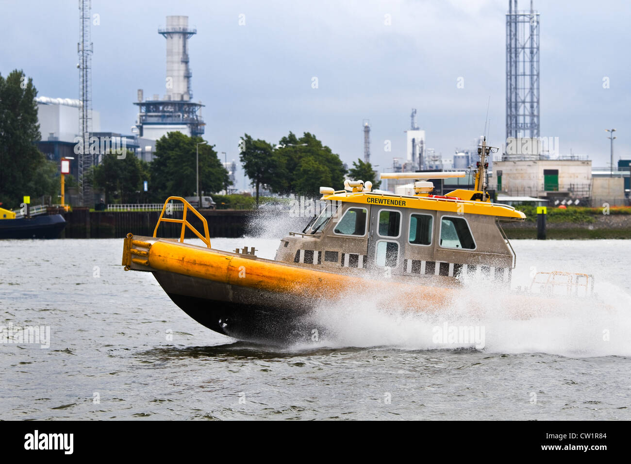 Crewtender passing by at full speed in port - with industrial ...