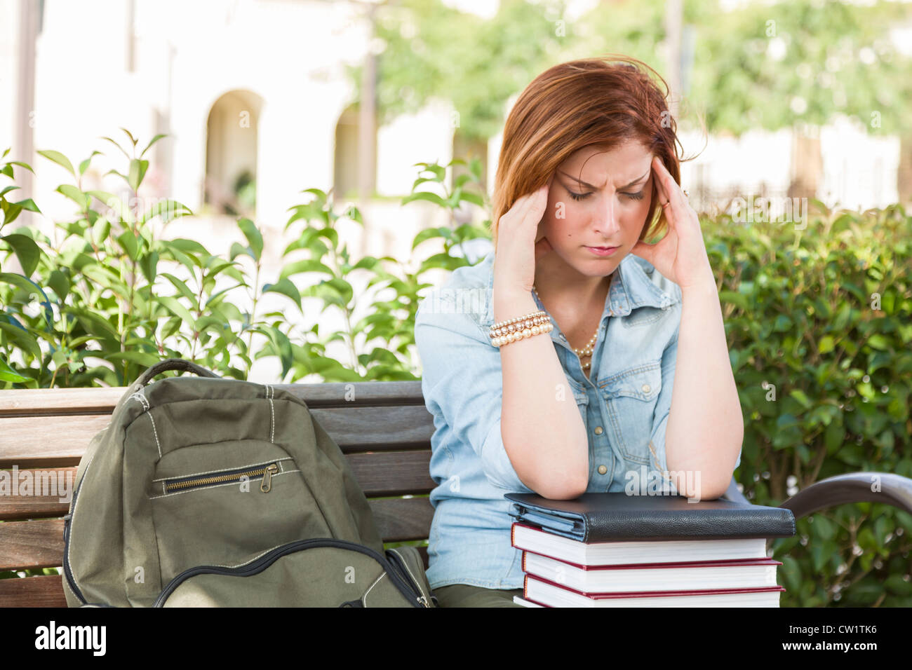 Young Female Student with Headache Sitting with Books and Backpack on ...