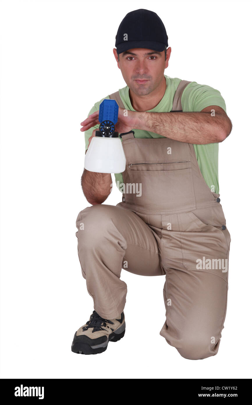 Man kneeling with paint sprayer Stock Photo - Alamy
