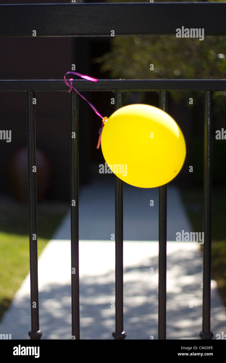 Yellow balloon attached to a gate Stock Photo - Alamy