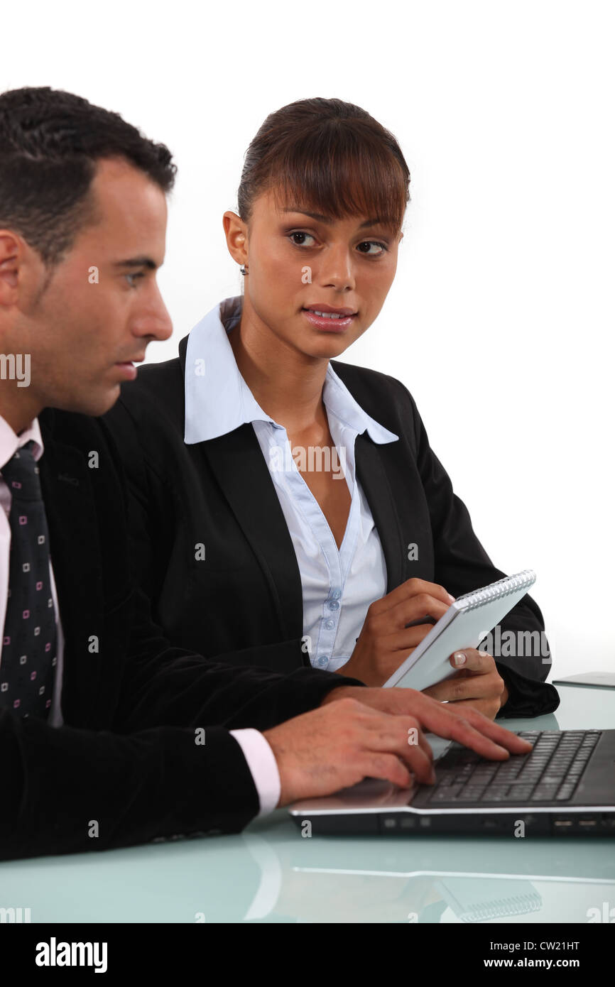 Woman taking notes as a businessman uses a computer Stock Photo - Alamy