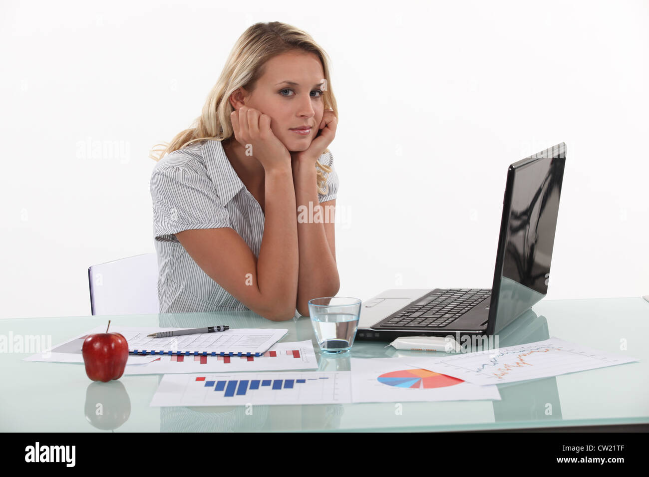 Woman sat at desk with glass of water and apple Stock Photo - Alamy