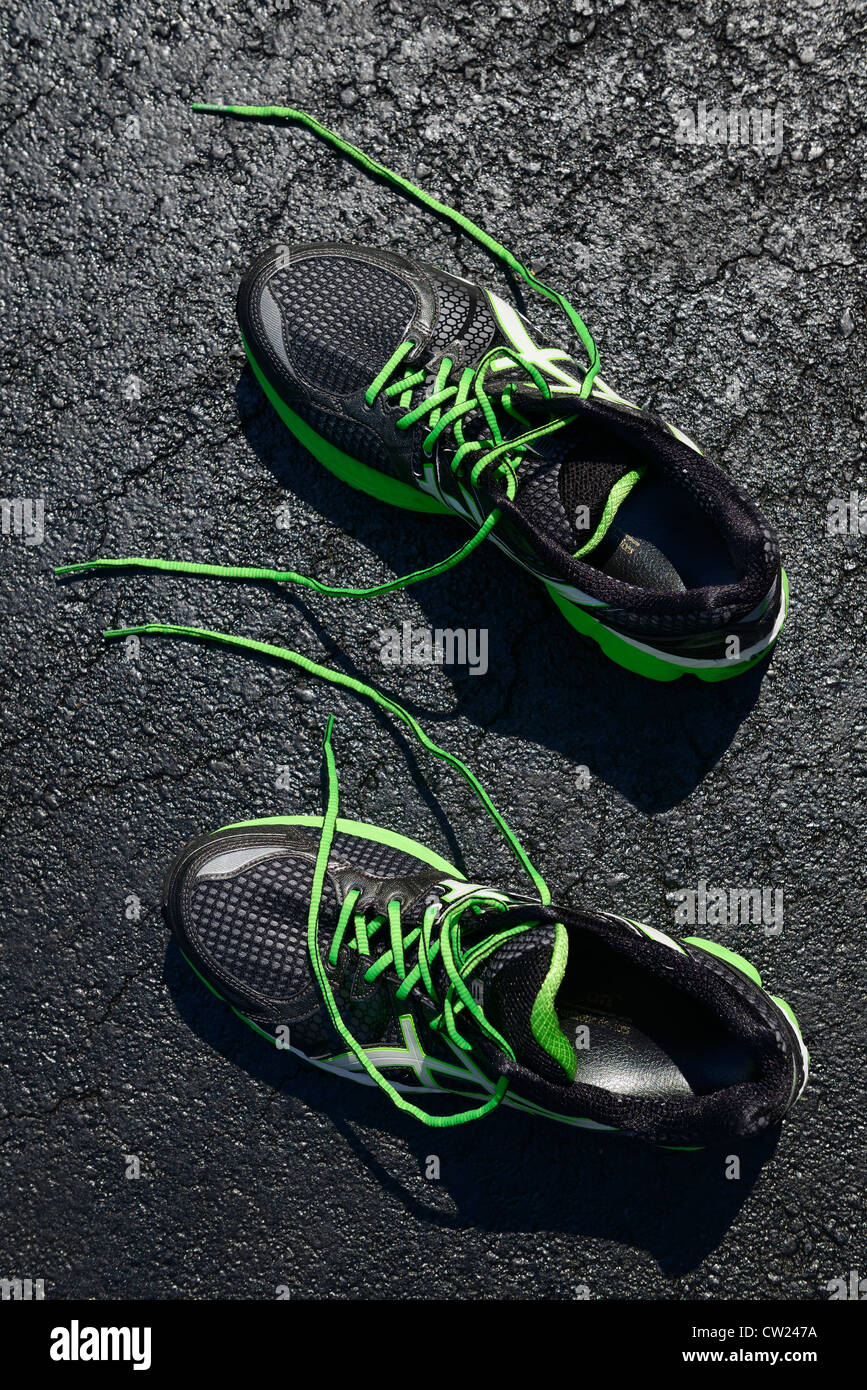 Empty new running shoes in the sun on a black asphalt road Toronto ...