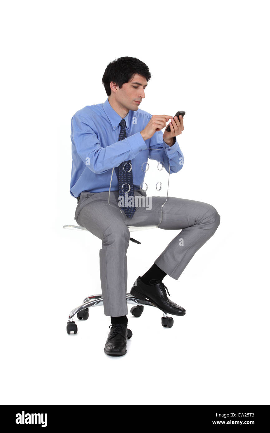 Businessman sat on chair sending SMS Stock Photo - Alamy