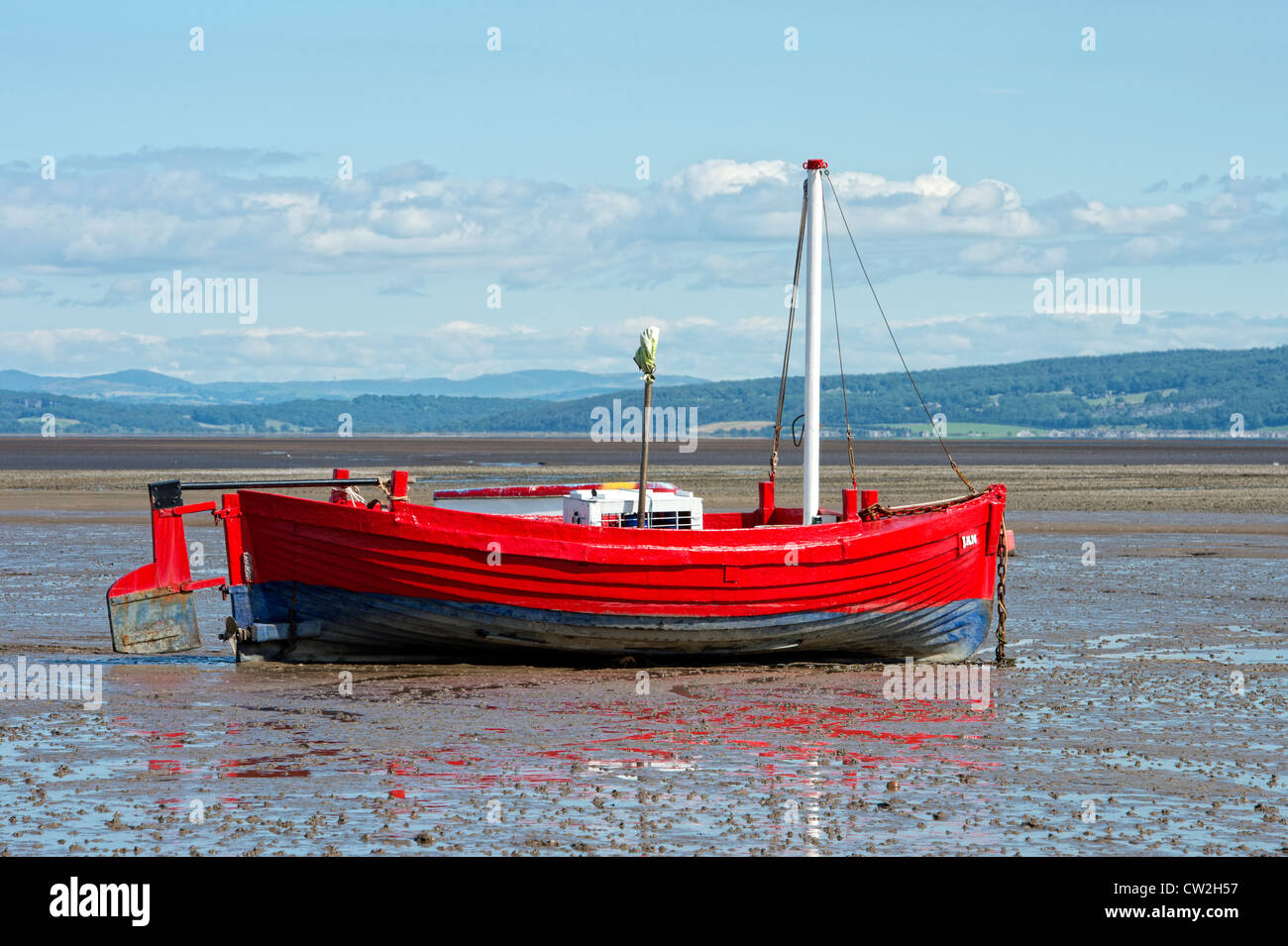 Red wooden fishing boat beached by the ebb tide in Morecambe Bay ...