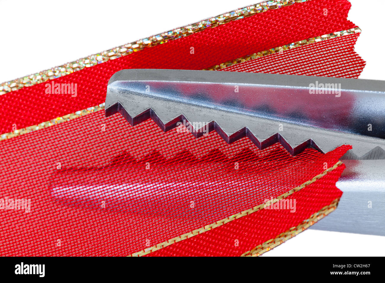 Close up of pinking shears cutting red christmas ribbon with gold edges ...