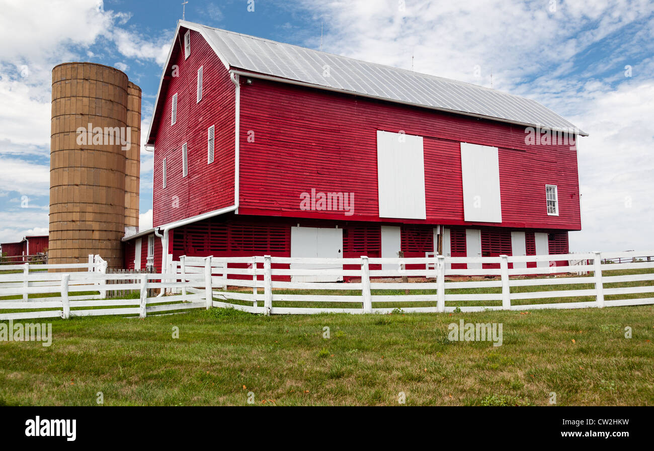 Red painted wooden barn with white door on farm in traditional US style ...
