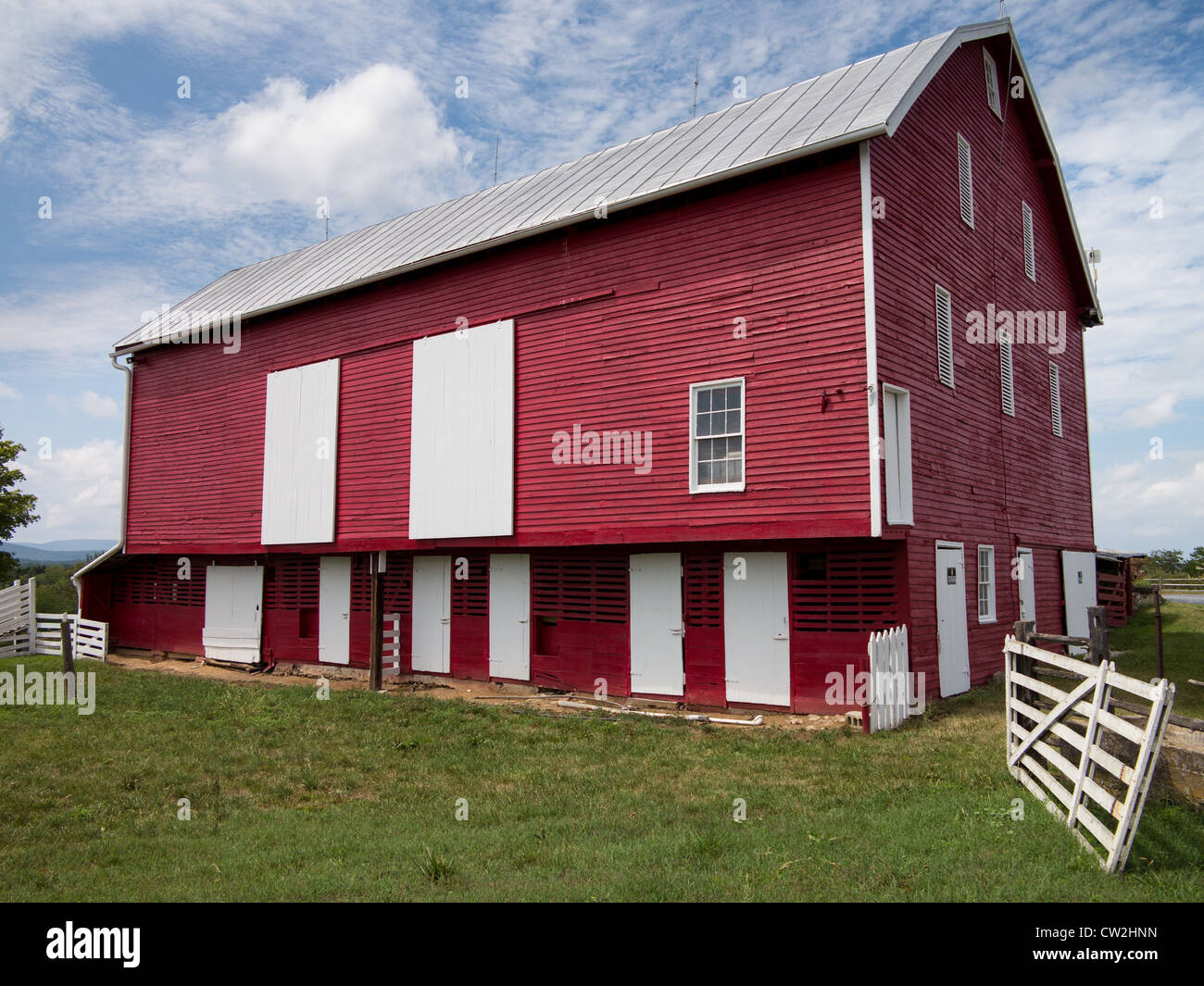 Red painted wooden barn with white door on farm in traditional US style ...