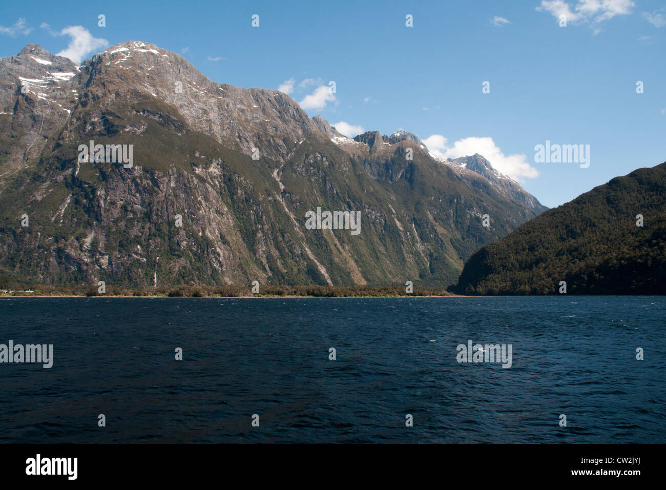 Steep mountain slopes dip into Milford Sound, an important touristic ...