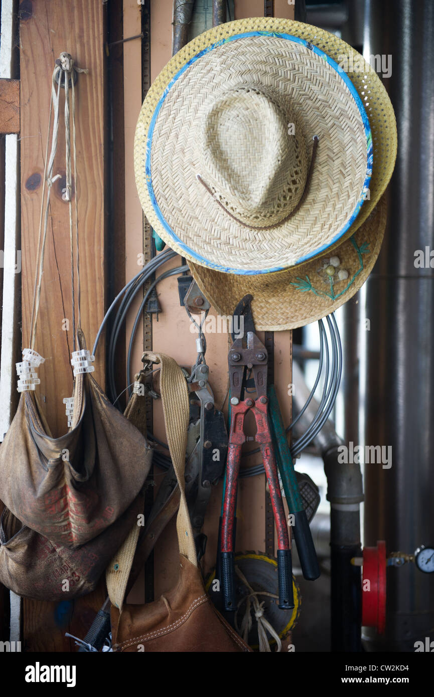 Farming tools and straw hat hanging up Stock Photo - Alamy