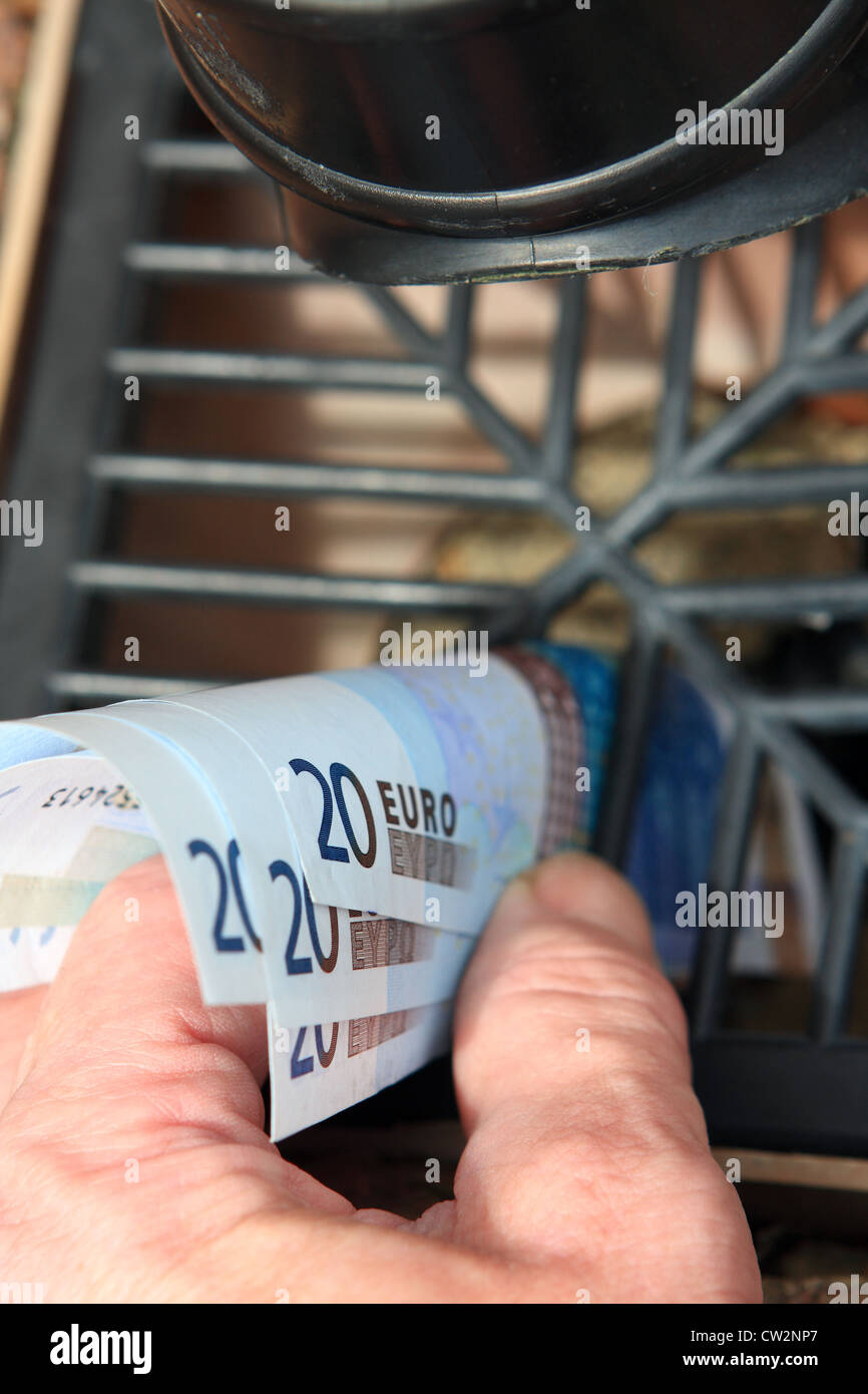 A hand pulling euro notes out of a drain Stock Photo - Alamy