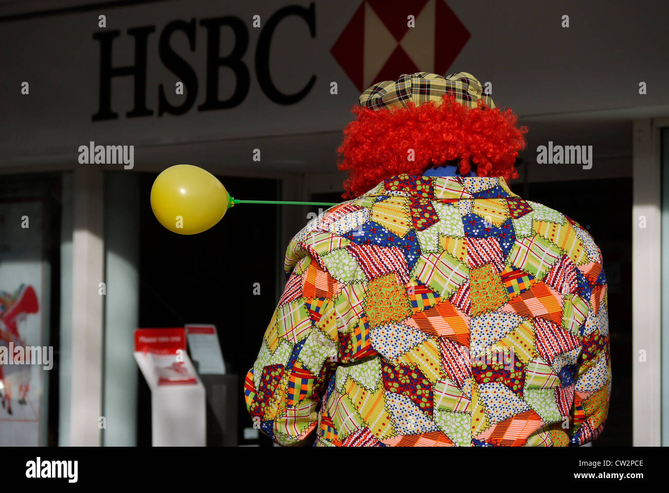 Back view of a Clown in a multi coloured stitched jacket and a balloon ...