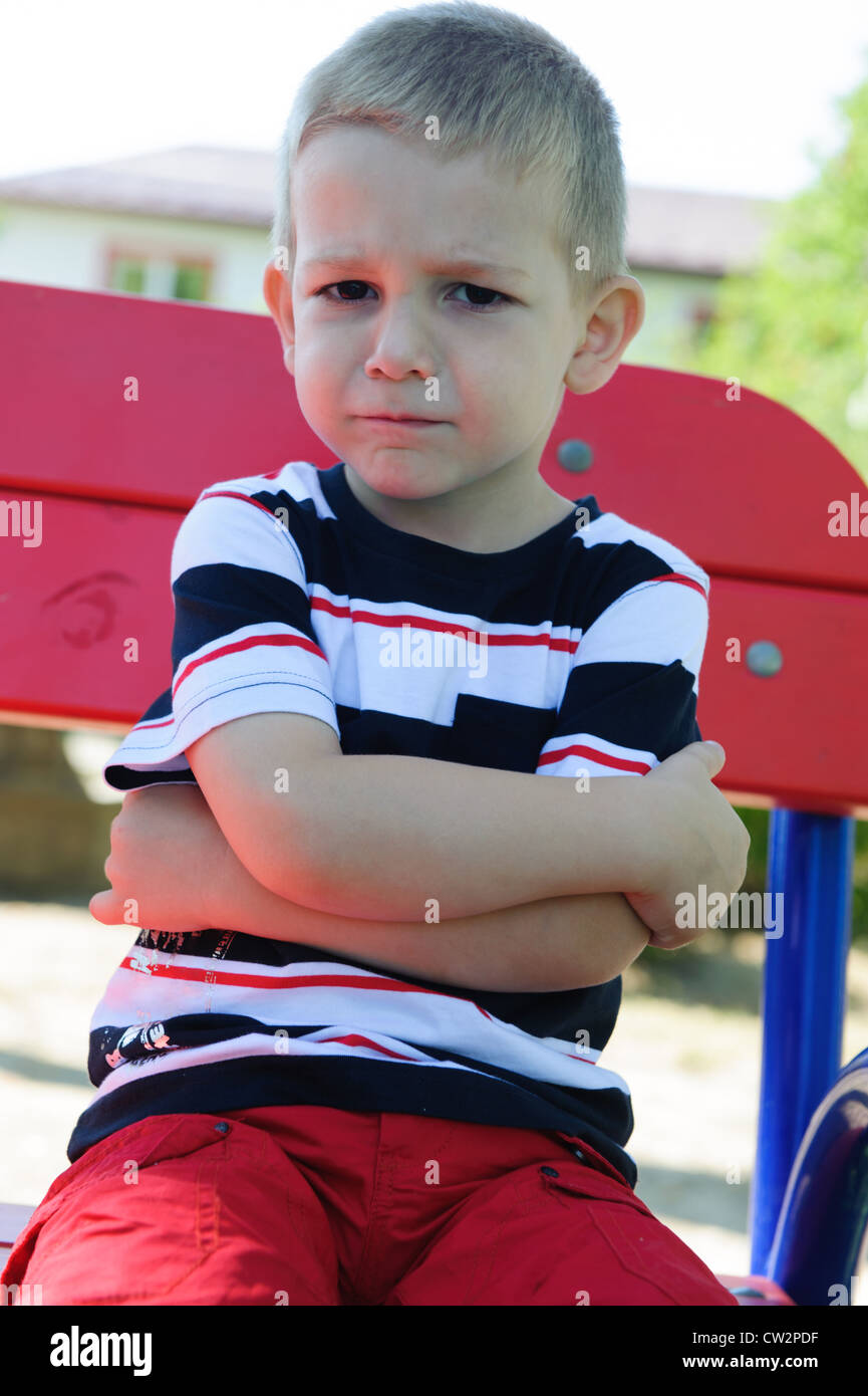 Serious little boy with negative emotons sitting at playground Stock ...
