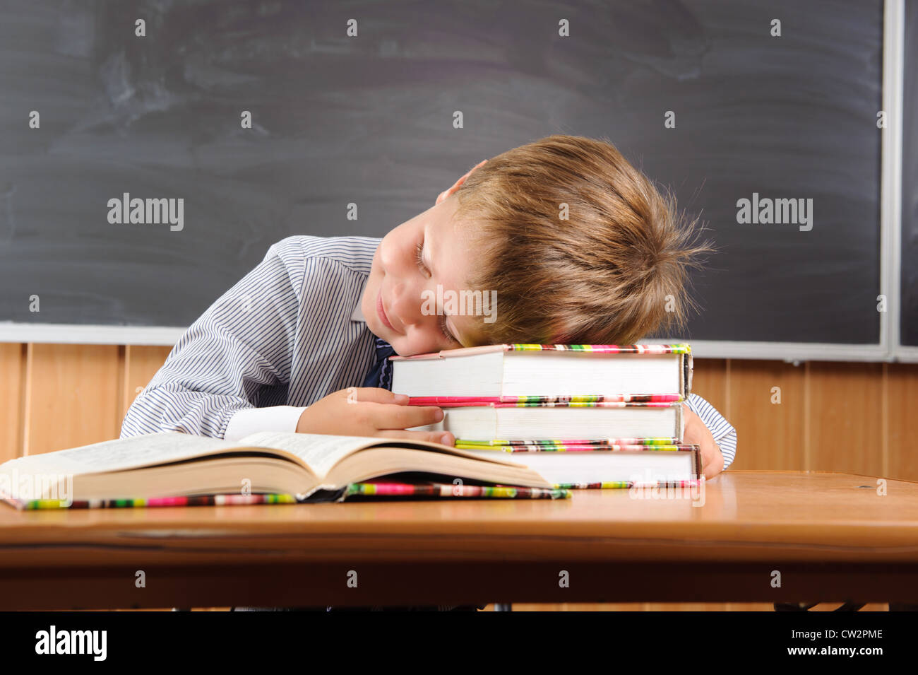 Sleeping elementary aged boy sitting at the desk with books Stock Photo ...