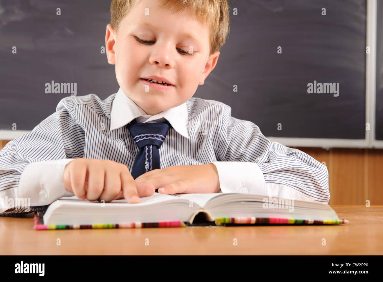 Cute elementary aged boy sitting at the desk with books Stock Photo - Alamy