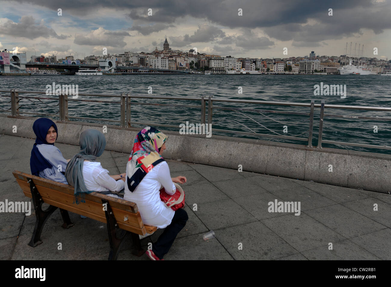 Turkish young women sitting on a bench overlooking the golden horn ...