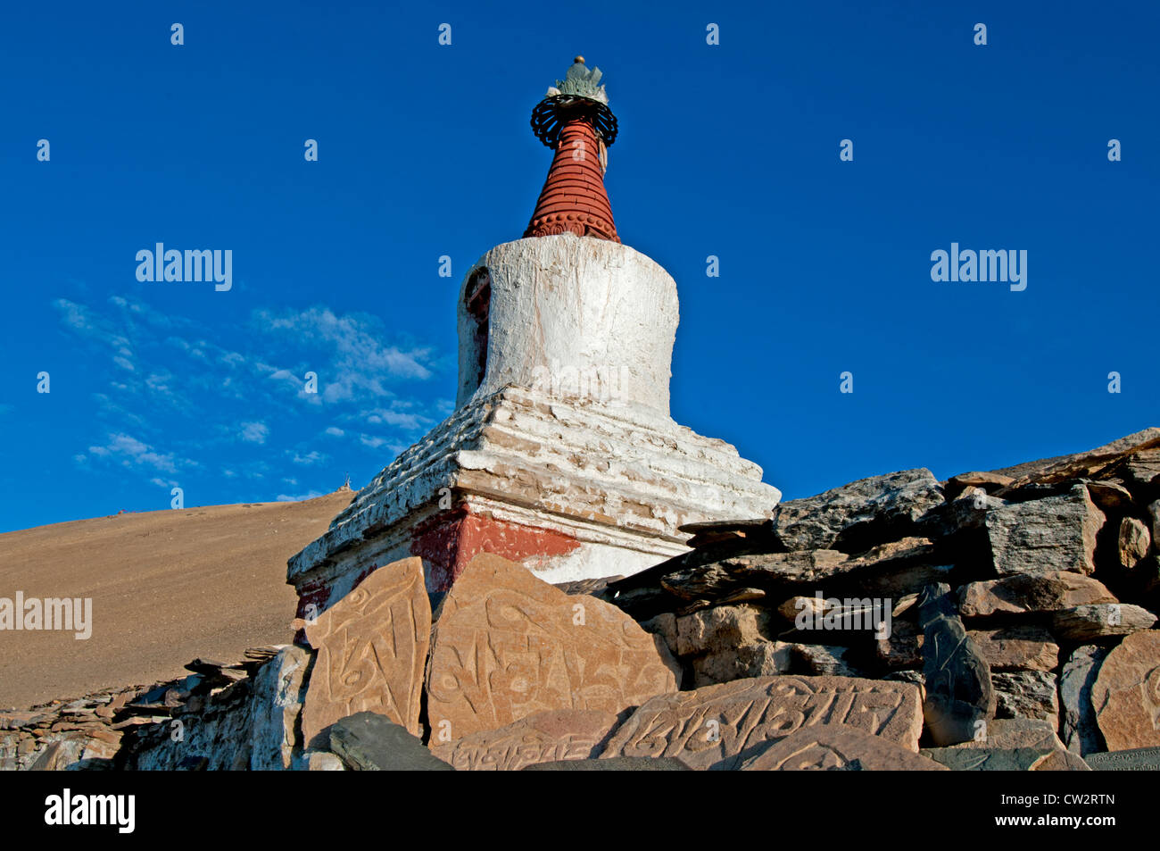 A handmade wall, prayer stones and a chorten against a blue sky in the ...