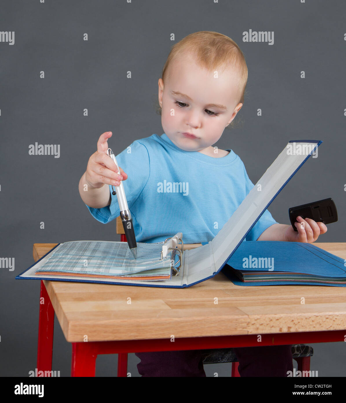 baby with paperwork at wooden desk in grey background Stock Photo - Alamy
