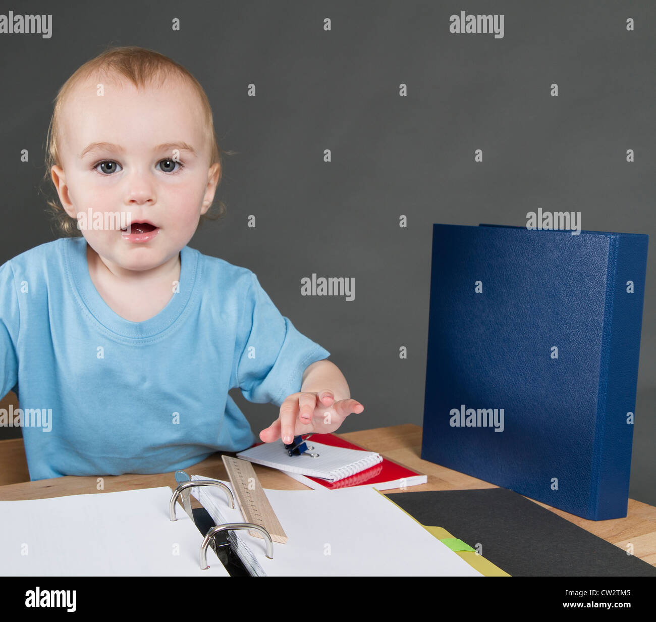 child with paperwork at small desk in grey background Stock Photo - Alamy