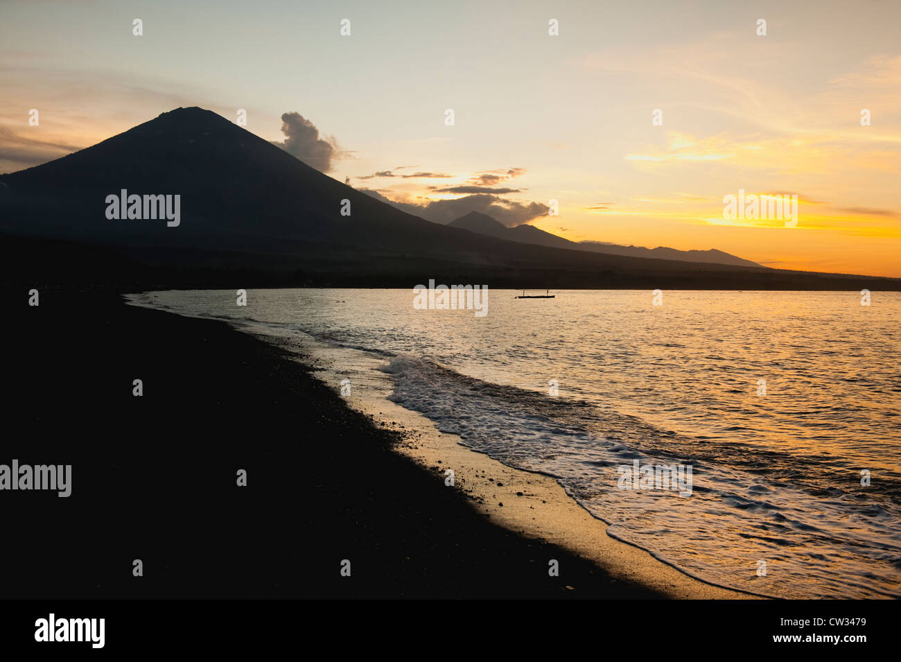 The volcanic black sand beach with the volcano Gunung Agung in the ...