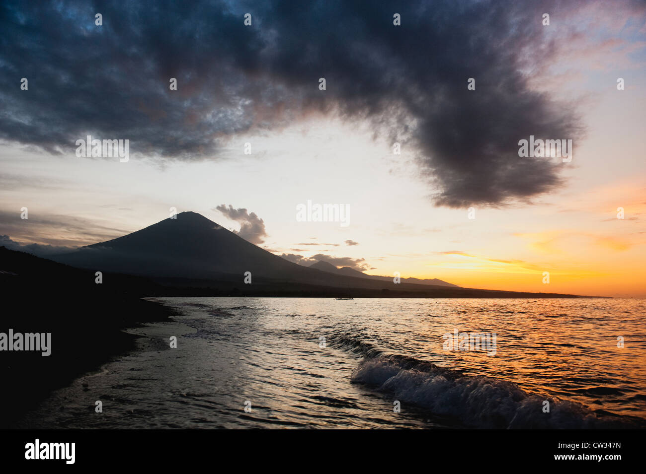 The volcanic black sand beach with the volcano Gunung Agung in the ...