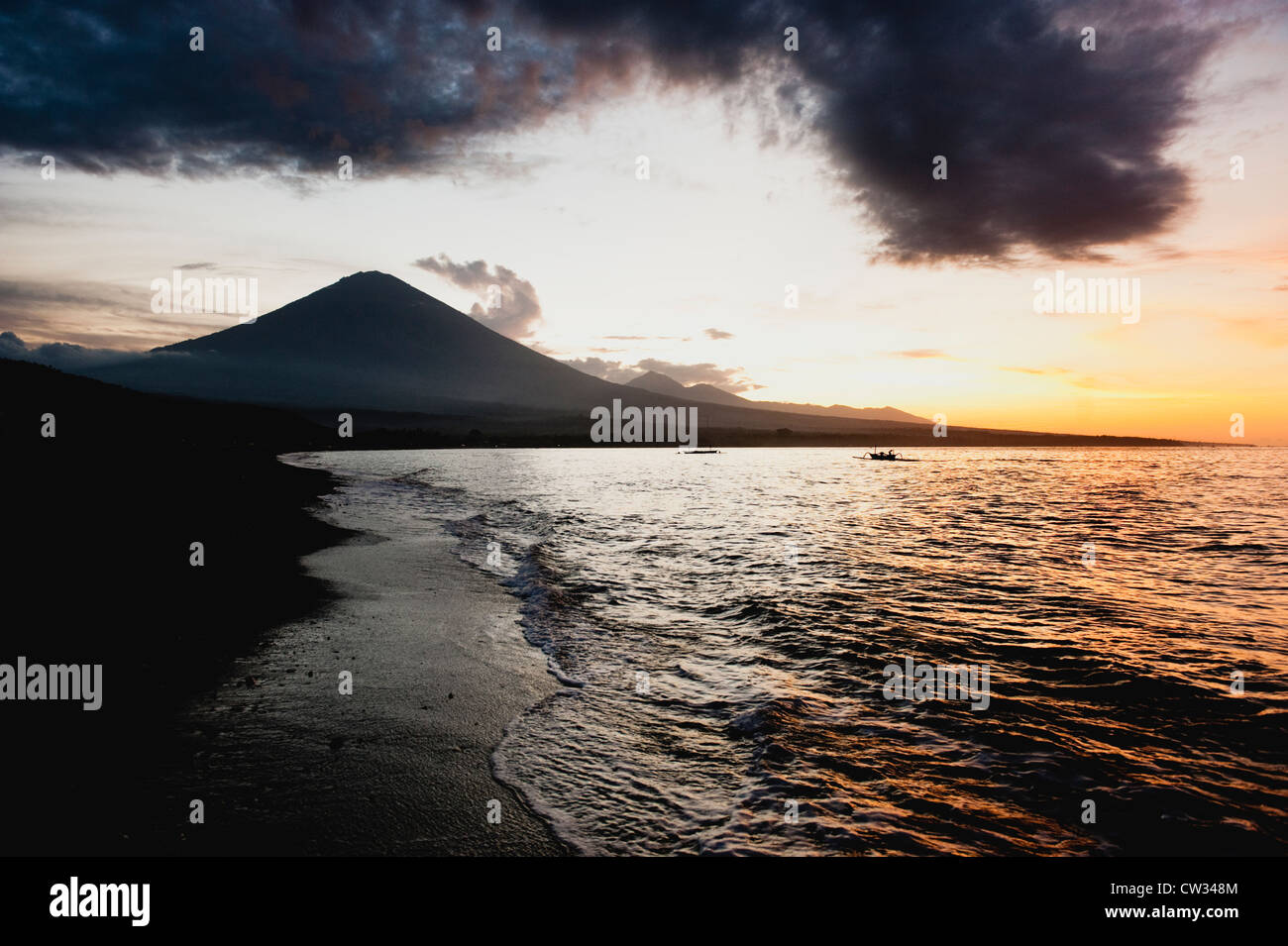 The volcanic black sand beach with the volcano Gunung Agung in the ...